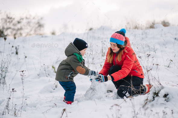 Mother and little toddler boy walking in the winter forest and having fun with snow. Stock Photo ...