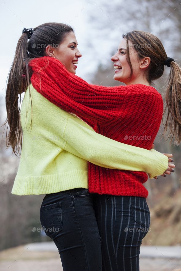 Smiling women in sweaters hugging in park Stock Photo by carlesmiro