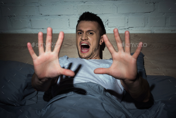 scared young man screaming while having nightmares at night Stock Photo ...