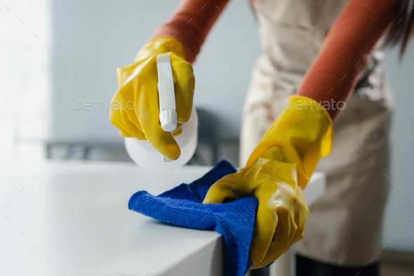 Cleaning desk surface in office with sanitizer spray, wear gloves and ...
