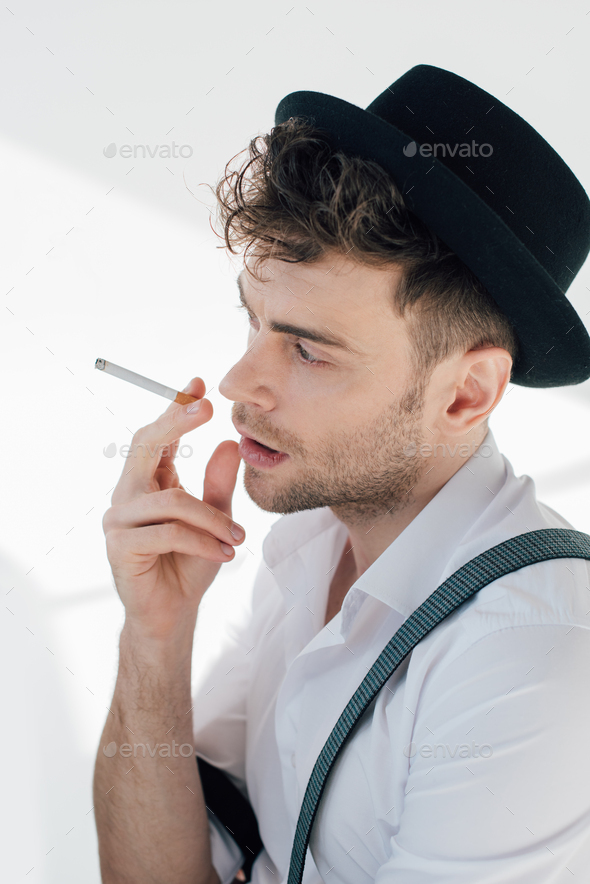 handsome man in white shirt and black hat smoking cigarette Stock Photo ...