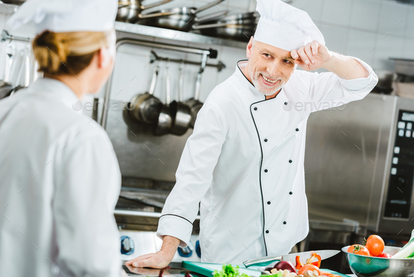 selective focus of male and female chefs in uniform looking at each ...