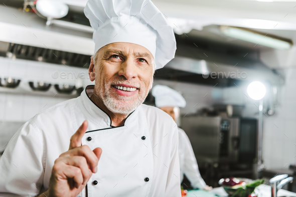 handsome smiling male chef in uniform and cap doing idea gesture in ...