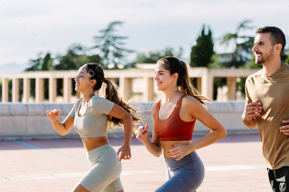 Three young friends running together outdoors. Stock Photo by xapdemolle
