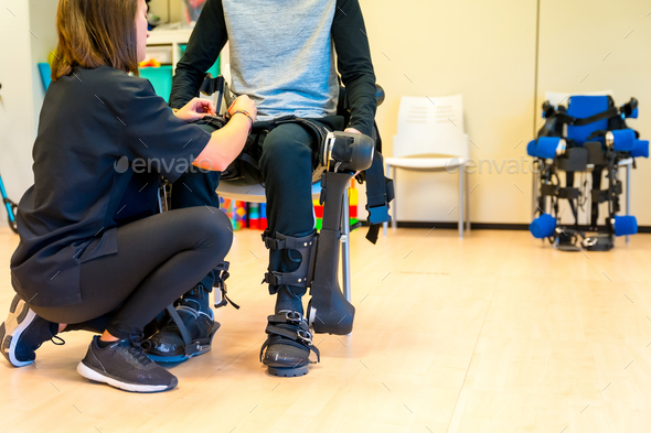 Mechanical exoskeleton. Female physiotherapist helping disabled person ...