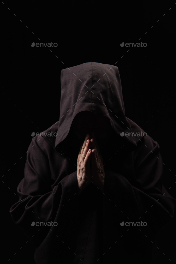 monk in hooded robe with praying hands and obscured face isolated on ...