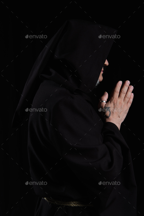 side view of tattooed priest with obscured face praying isolated on ...