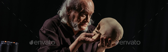medieval philosopher with grey hair looking at human skull isolated on ...