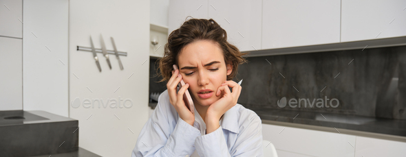 Portrait of woman sitting at home with confused, sad face, talking on ...