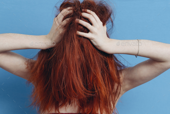 red-haired woman touching her head with hands emotions tousled hair ...