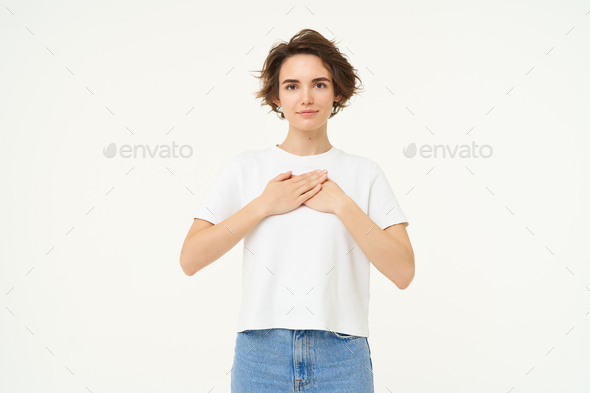 Portrait of brunette woman with hands on chest, looks with care and ...
