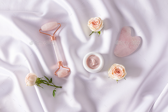 Set of cosmetics and tools on white satin background with live rosebuds ...