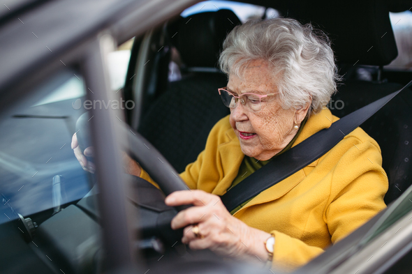Focused senior woman driving car alone, holding steering wheel firmly ...