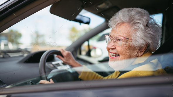 Happy senior woman driving car alone, enjoying car ride. Safe driving ...