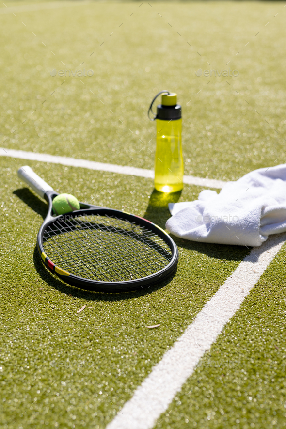 Close up of tennis ball, racket, towel and water bottle at tennis court ...