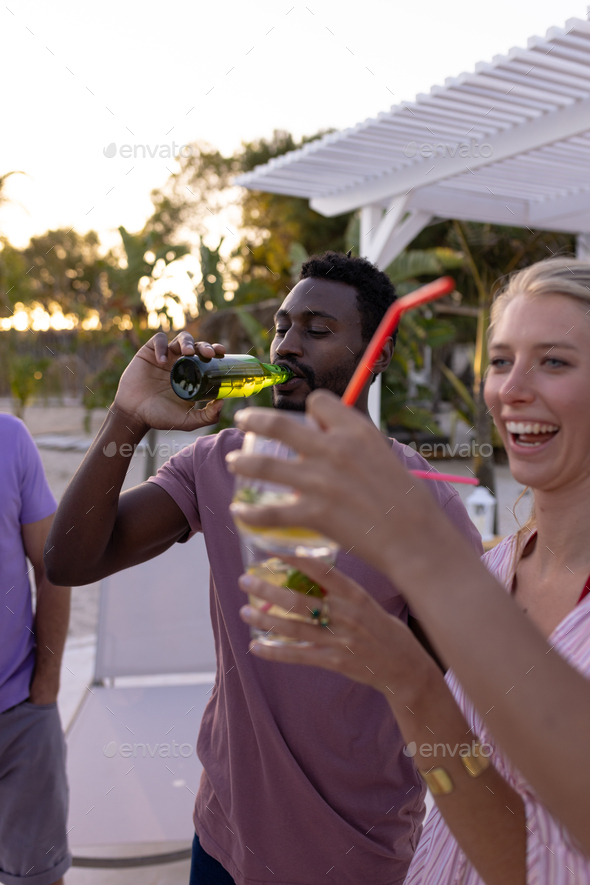 Happy diverse friends having party by swimming pool, drinking cocktails ...