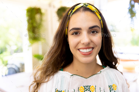 Close-up portrait of smiling biracial young woman wearing yellow ...