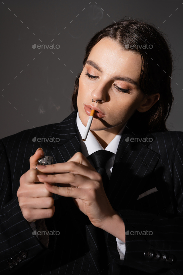 portrait of young model in formal wear lighting cigarette isolated on ...