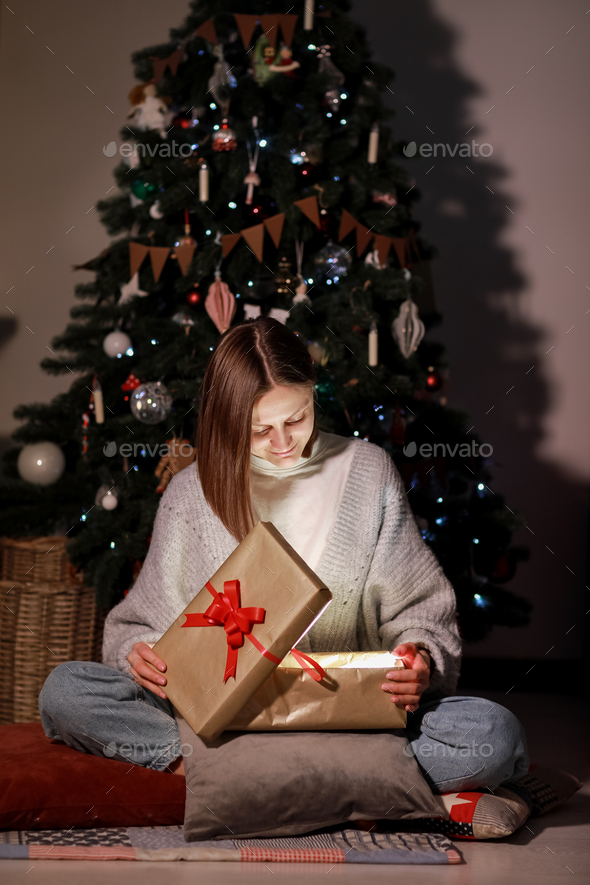 The Magic Of Christmas. Amazed young beautiful woman opening xmas gift ...
