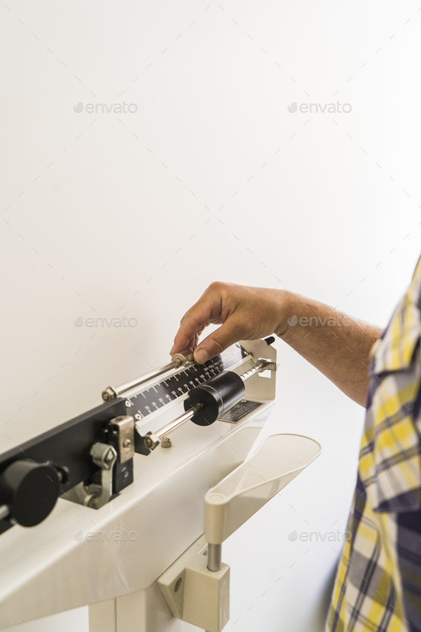Close-up of man on weighing scale in nutritionist's office. Vertical ...