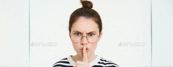 Image of serious woman in glasses, teacher shushing, makes shush, hush ...