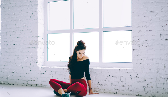 Attractive Caucasian woman sitting near window in white studio gym ...