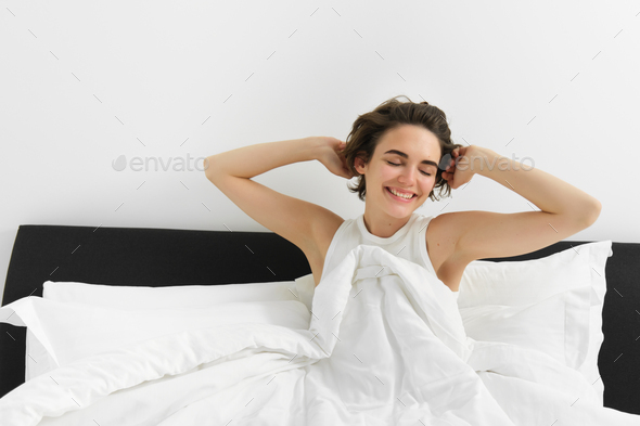 Portrait of woman feeling satisfied after good sleep, stretching hands ...