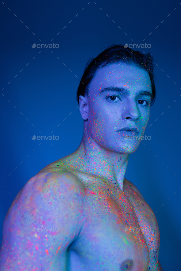 portrait of youthful and handsome shirtless man in multicolored neon ...