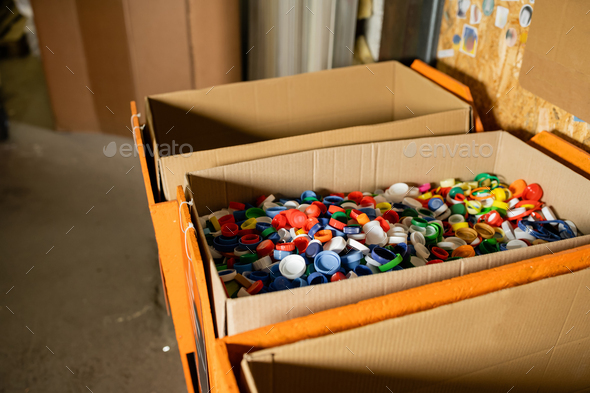 Cardboard boxes with colorful plastic caps for recycle in blurred waste ...