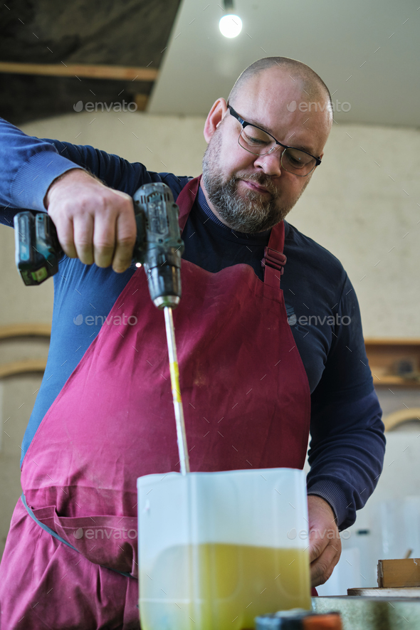 Man stirs epoxy, a process in creating durable finishes. Symbolizes the ...