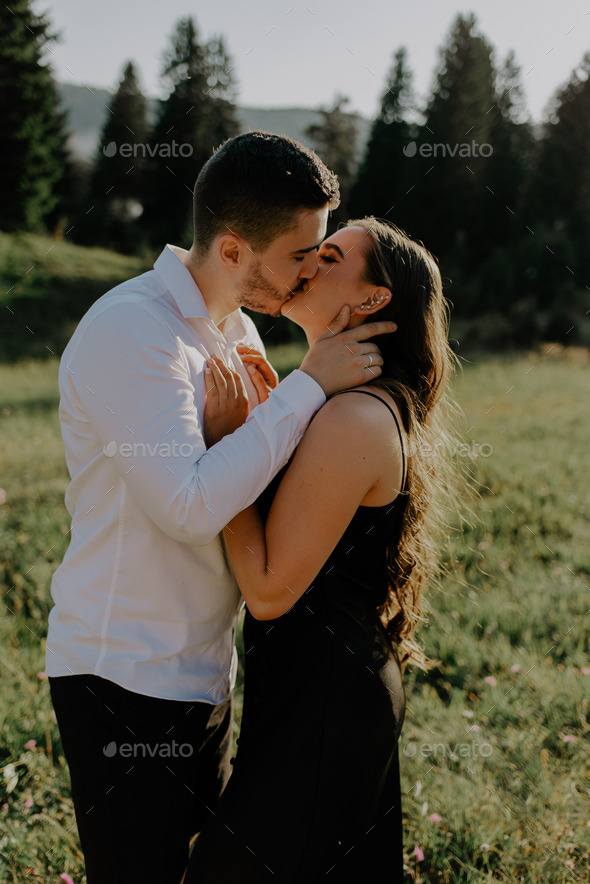 Vertical shot of a young romantic couple kissing on a meadow Stock ...