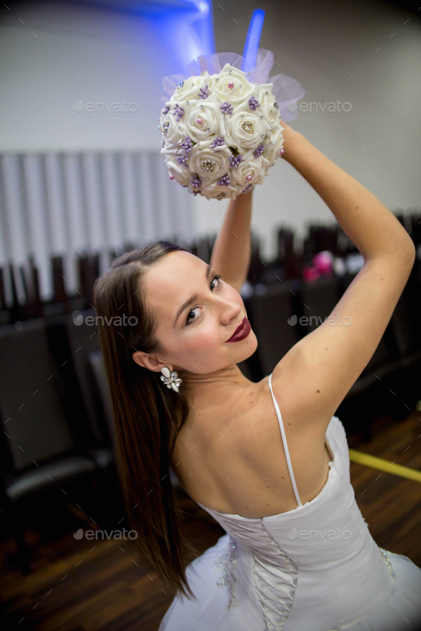 Back view of a young girl in a ball gown wedding dress throwing a white ...