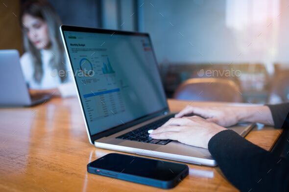 Female office worker working on a laptop computer from a wooden desk in ...