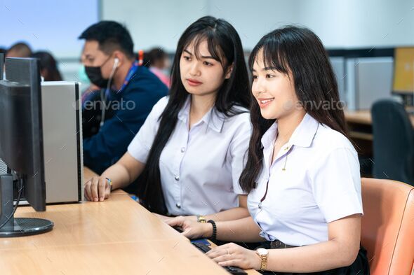 two asian female students in front of a computer Stock Photo by wirestock
