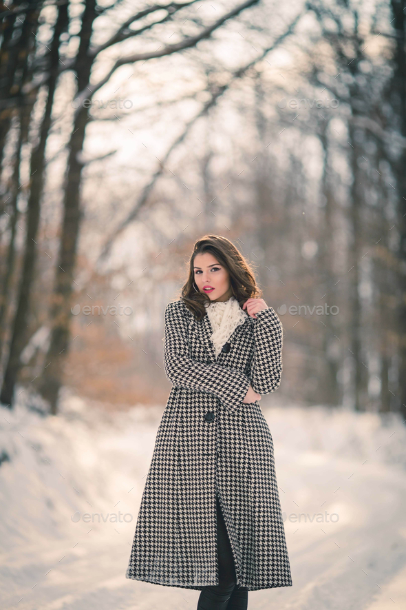 Full body shot of a brunette girl in a stylish winter outfit posing in ...
