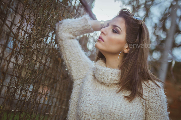 Side profile of a confident brunette woman leaning againstt a fence ...