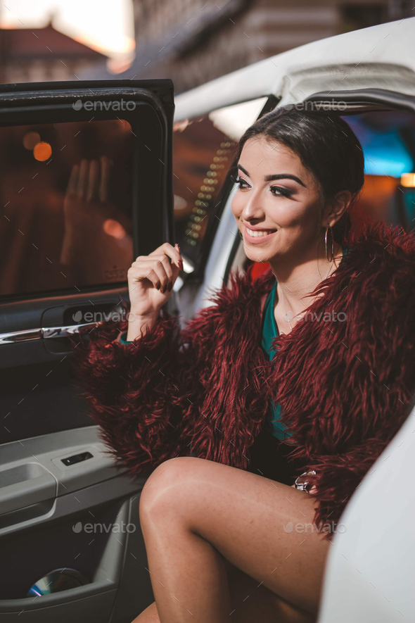 Pretty Caucasian lady with an evening dress and fur coat posing with ...