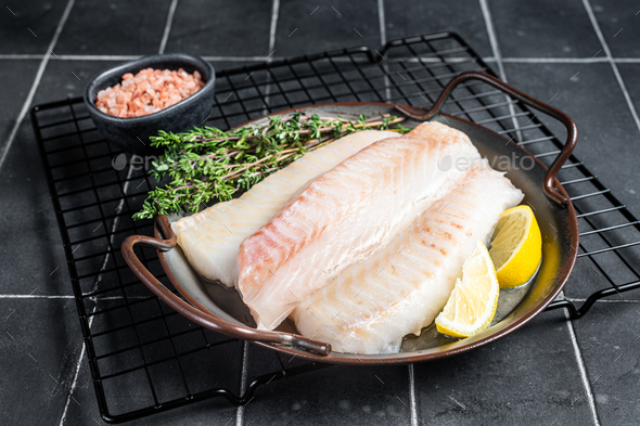 Fresh raw cod fish fillets with herbs served on steel tray. Black ...