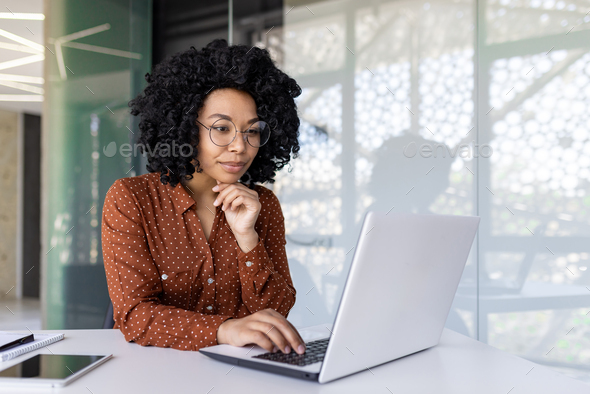 Serious thinking woman working with laptop, typing on keyboard ...