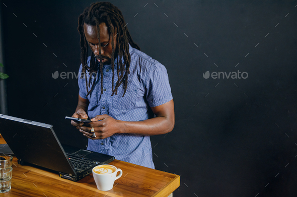 black business man with dreadlocks standing inside cafe working using ...