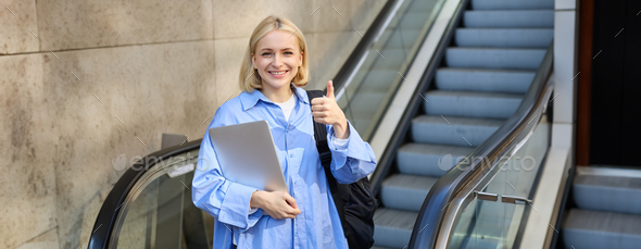 Portrait of young female model, student with backpack and laptop ...