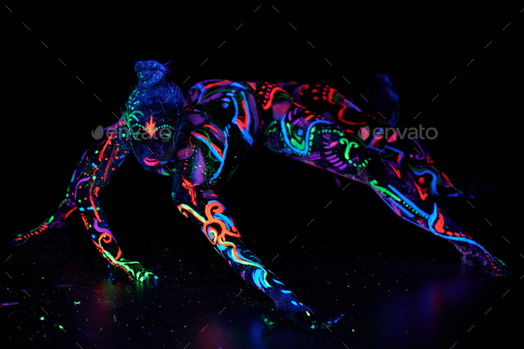 Art woman body art on the body dancing in ultraviolet light. Bright ...
