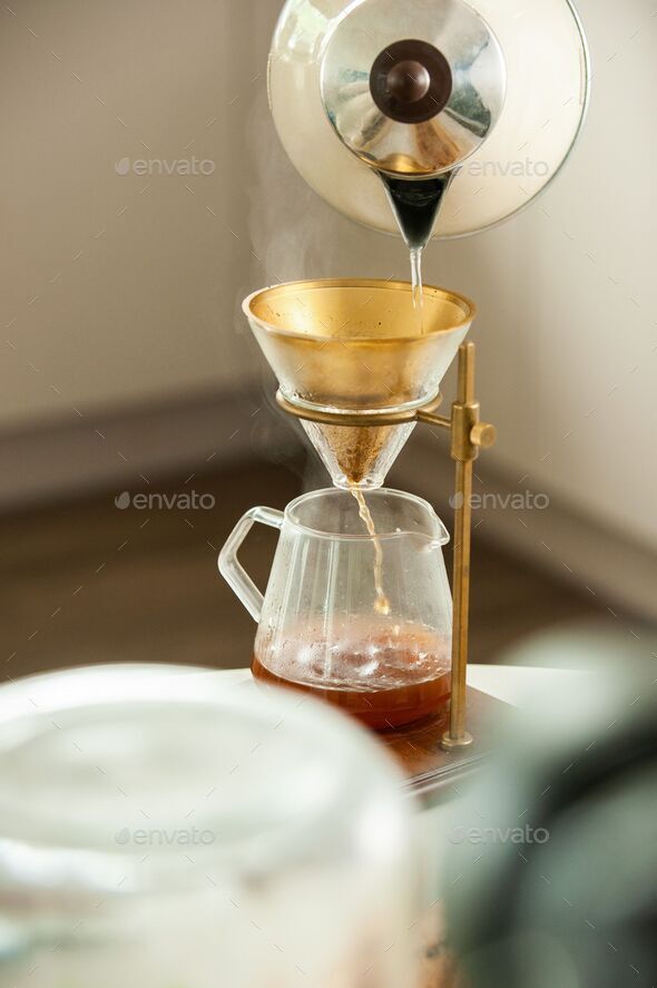 Vertical closeup of a coffee maker with a filter and coffee pouring to ...