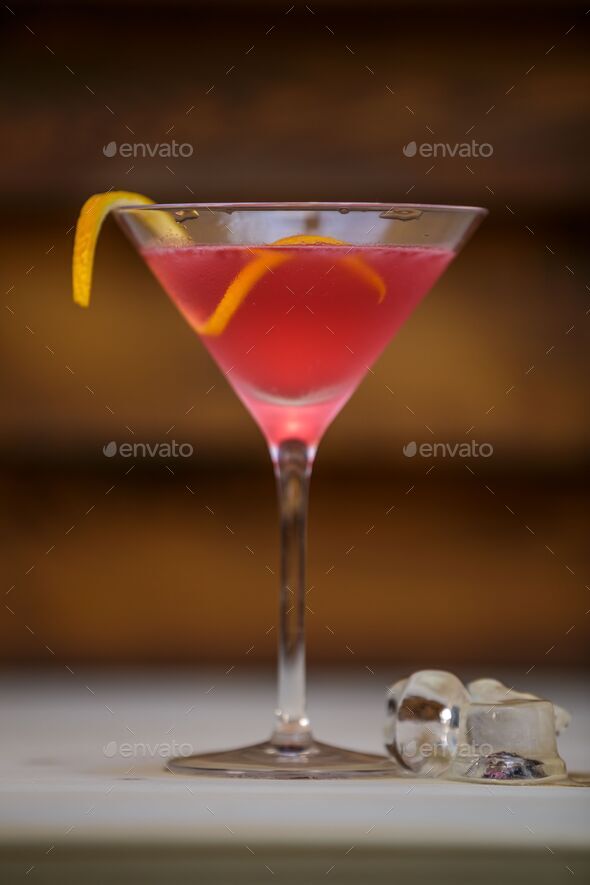 Shallow focus of a cosmopolitan cocktail with ice cubes and lemon on a ...