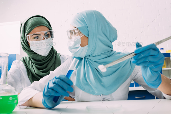 female muslim scientists holding test tube, tweezers and dry ice during ...