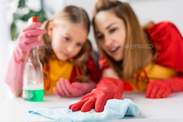 Selective focus of mother and daughter in red capes and rubber gloves ...