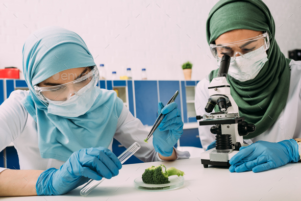 female muslim scientists looking through microscope and taking sample ...