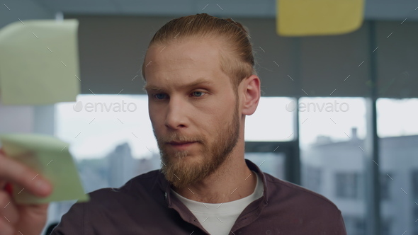 Focused manager putting sticker transparent wall at office closeup. Man ...