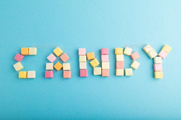 The inscription "candy" laid out with fruit chewing candies on blue ...
