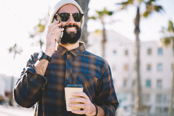 Cheerful hipster guy in sunglasses enjoying call conversation during ...